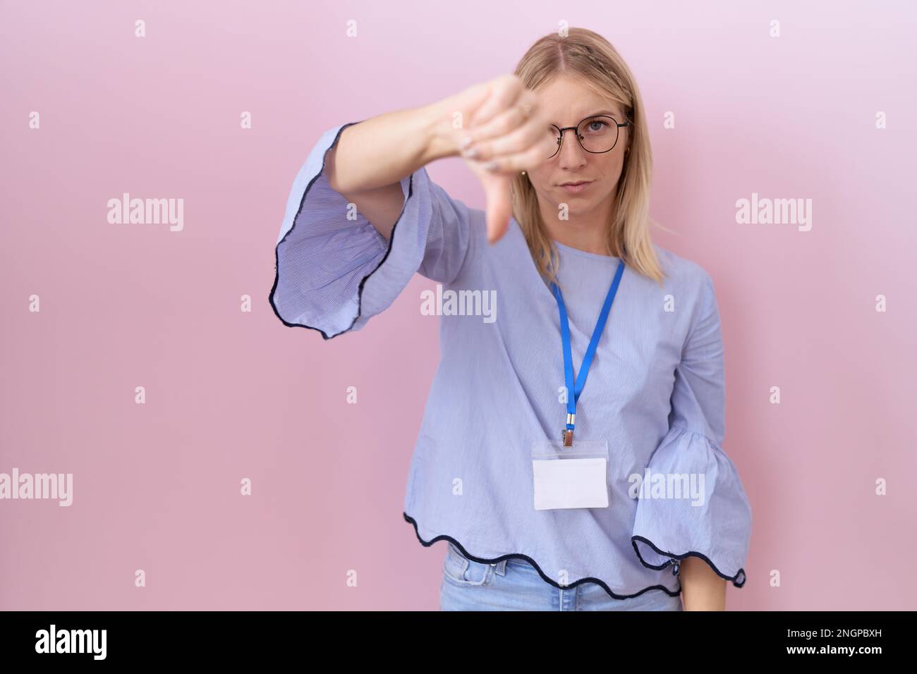 Young caucasian business woman wearing id card looking unhappy and ...