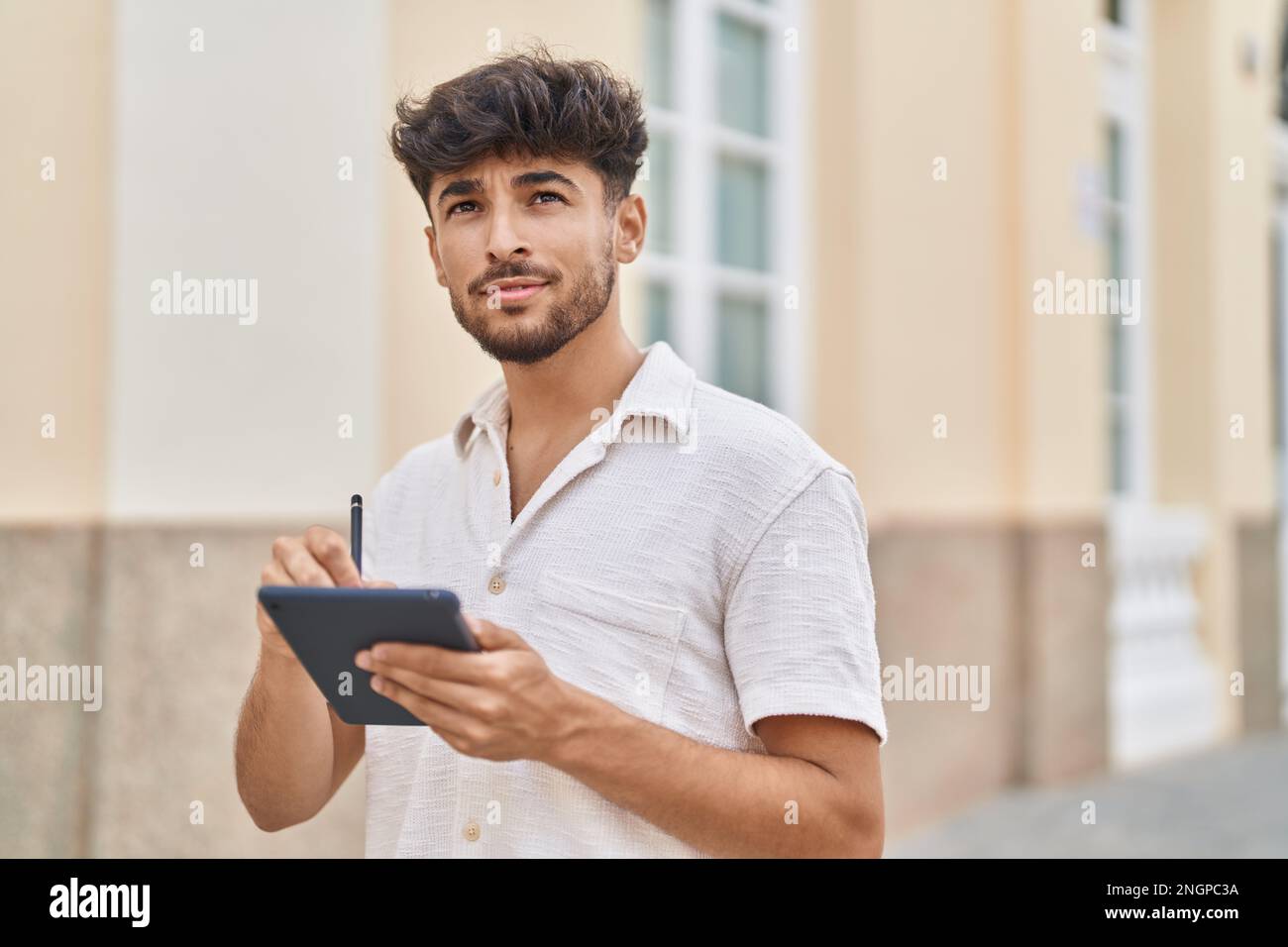Young arab man drawing on touchpad standing at street Stock Photo - Alamy