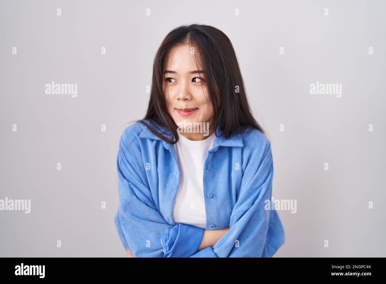 Young chinese woman standing over white background shaking and freezing ...