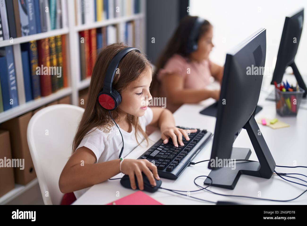 Two kids students wearing headphones using computer studying at ...