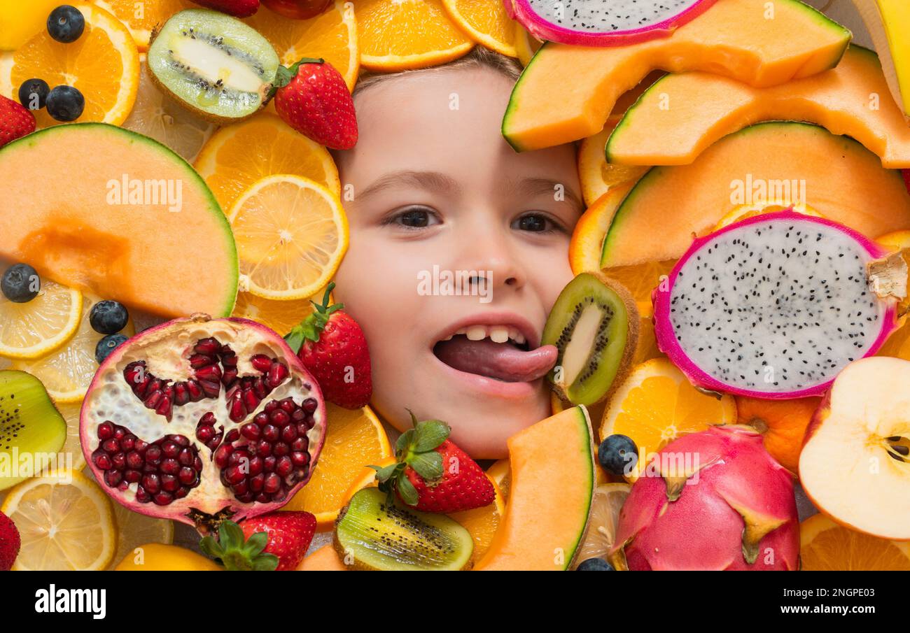 Kid tasting fruits. Kid licking kiwi. Frutit and child face close up ...