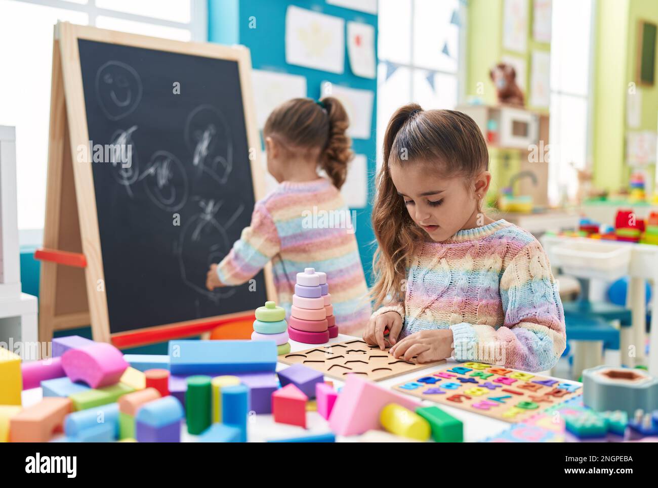 Two kids playing with maths puzzle game standing at kindergarten Stock ...