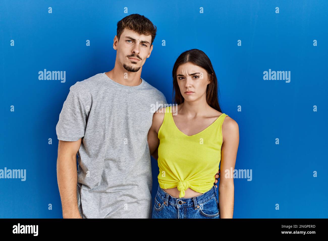 Young hispanic couple standing together over blue background depressed ...