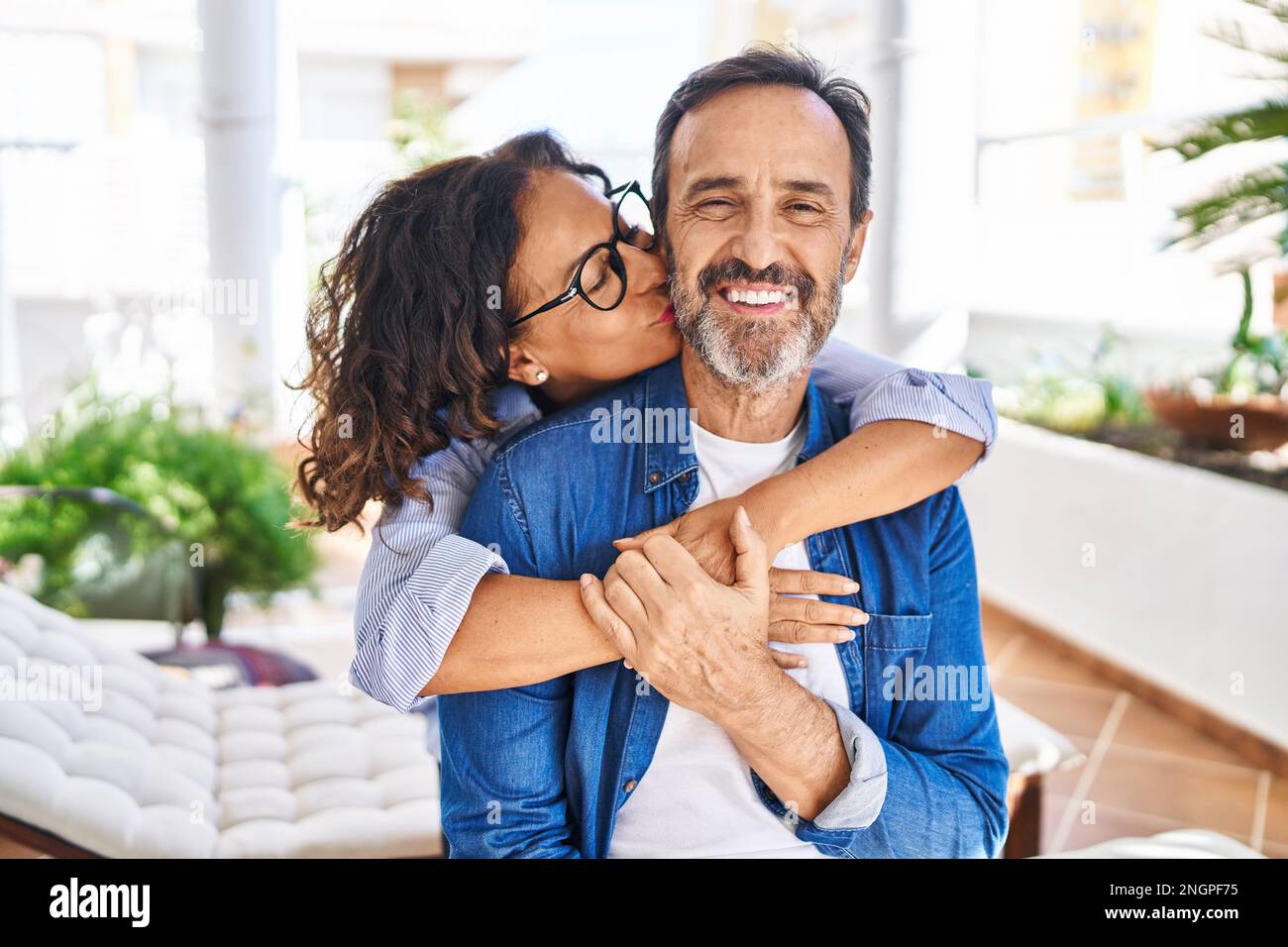 Middle age hispanic couple kissing and hugging each other sitting on ...