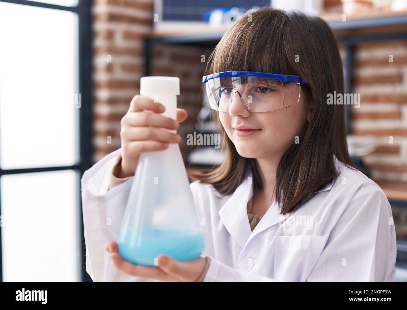 Adorable hispanic girl student holding test tube at laboratory ...