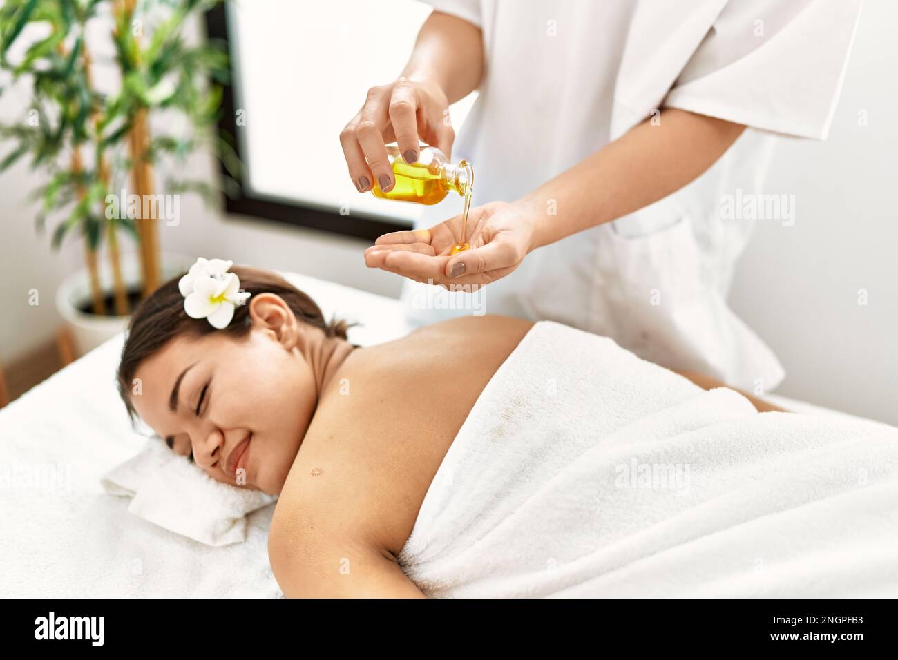 Young latin woman relaxed having back massage with oil at beauty center ...