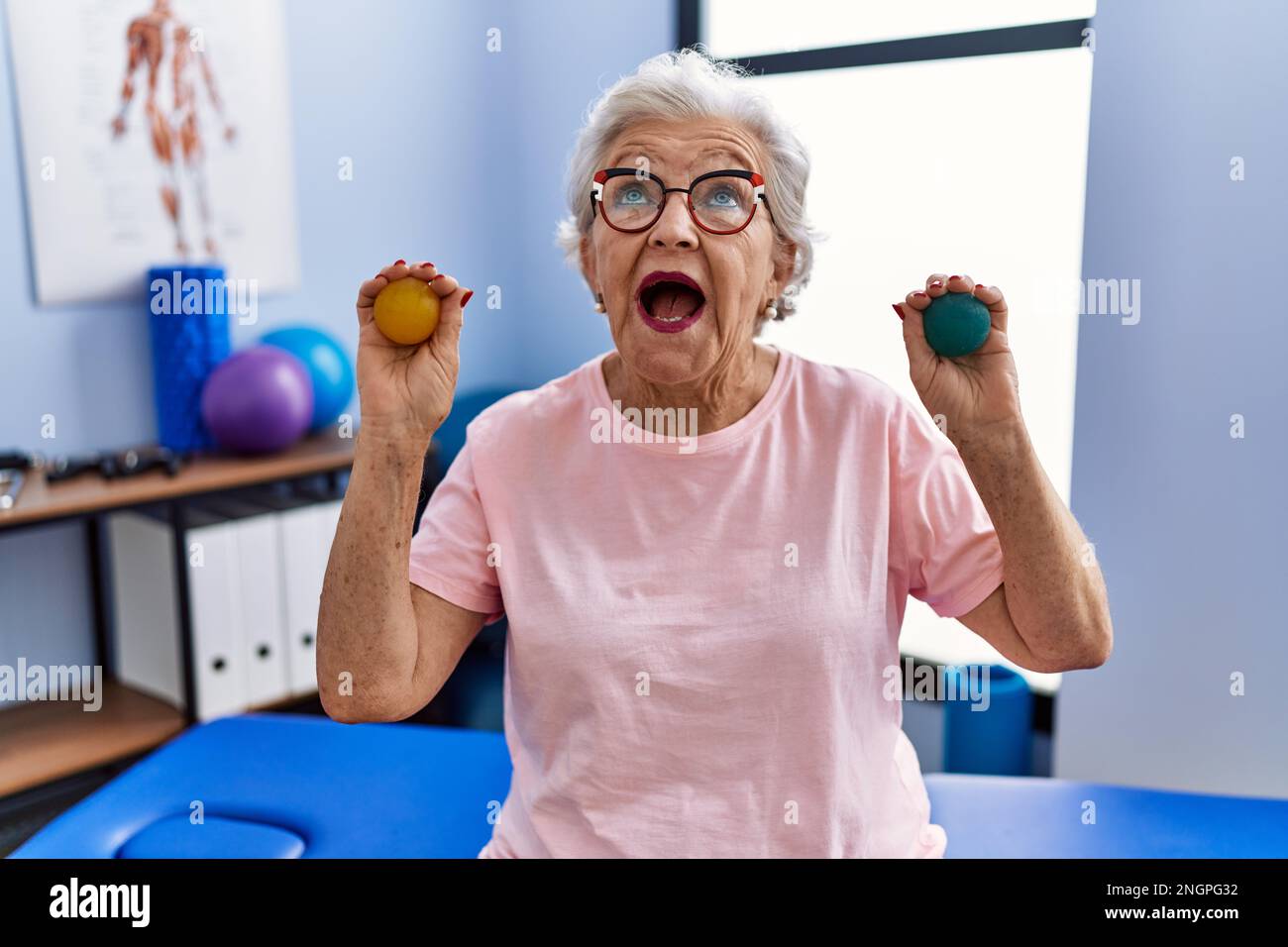 Senior woman with grey hair holding hands strength balls angry and mad ...