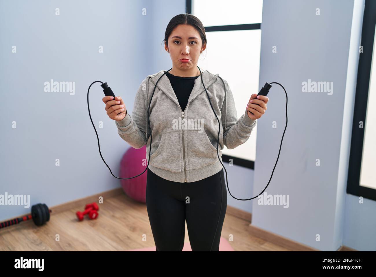 Young latin woman jumping with skipping rope depressed and worry for ...