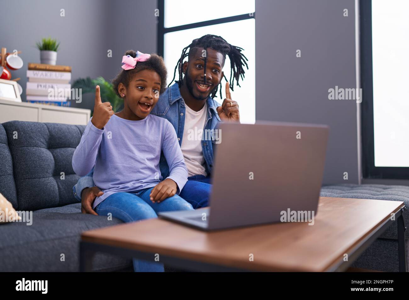 African father and daughter doing video call on laptop at home smiling ...