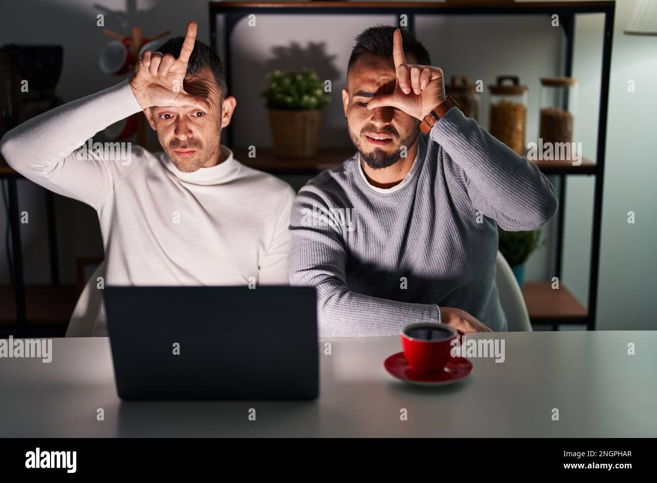 Homosexual couple using computer laptop making fun of people with ...