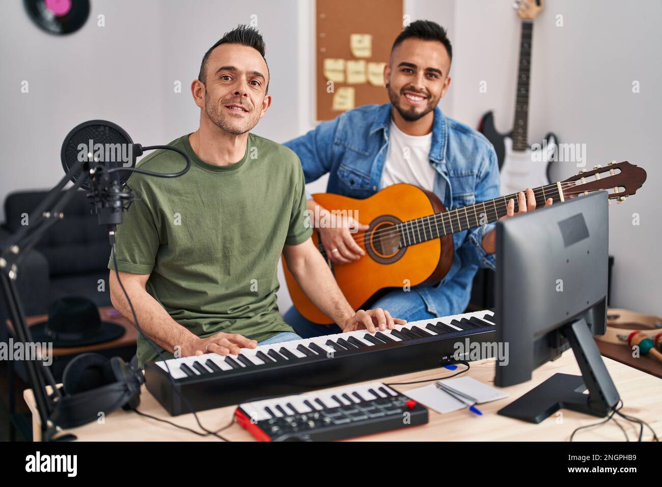 Two men musicians playing piano and classical guitar at music studio ...