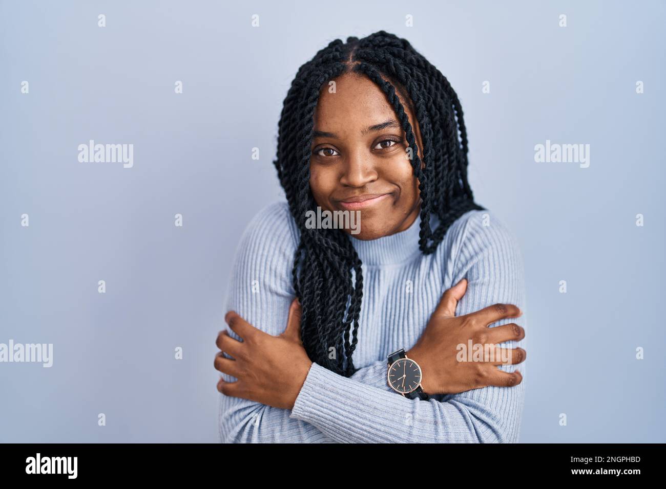 African american woman standing over blue background shaking and ...