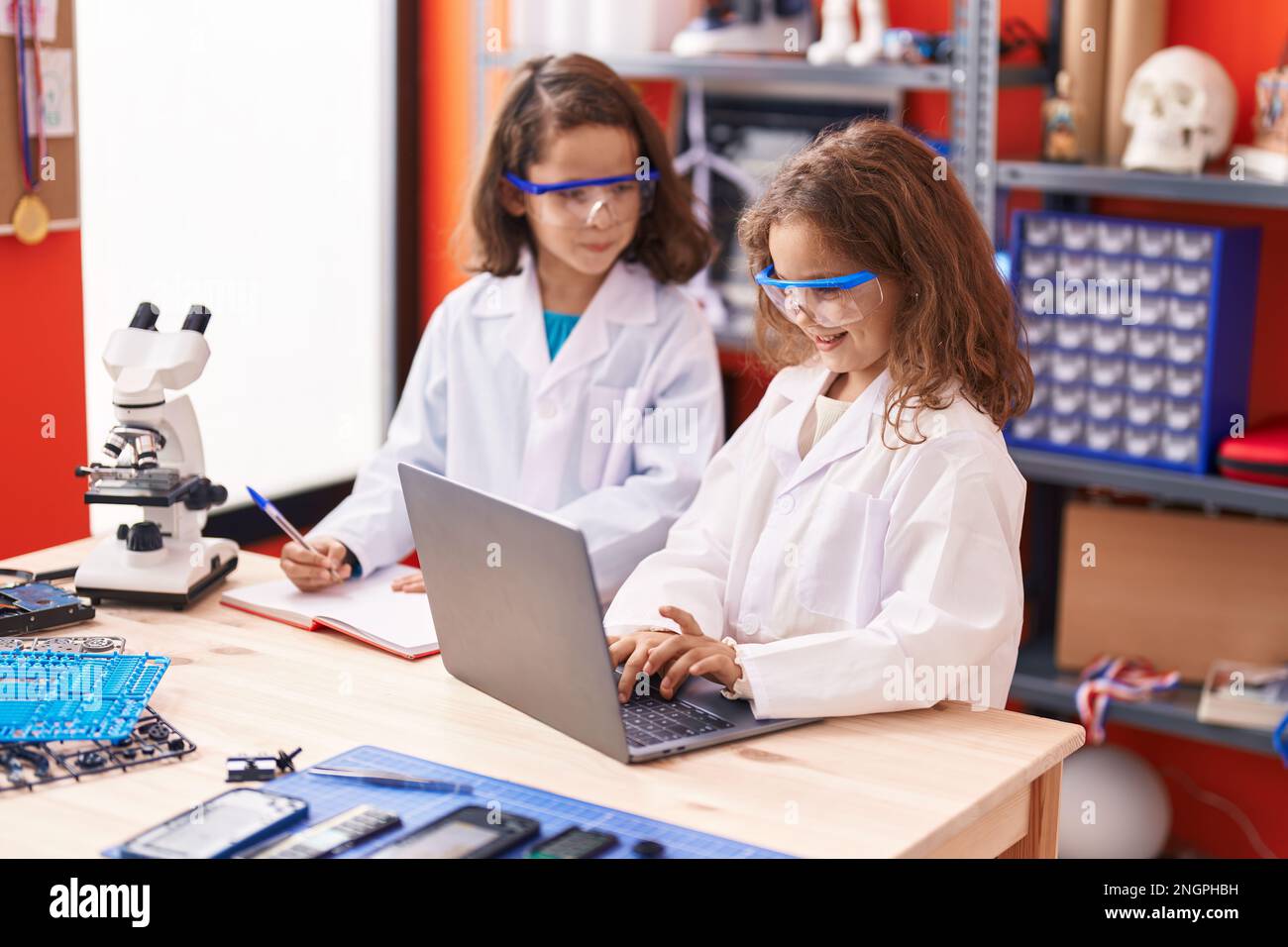 Two kids students using laptop writing on notebook at laboratory ...
