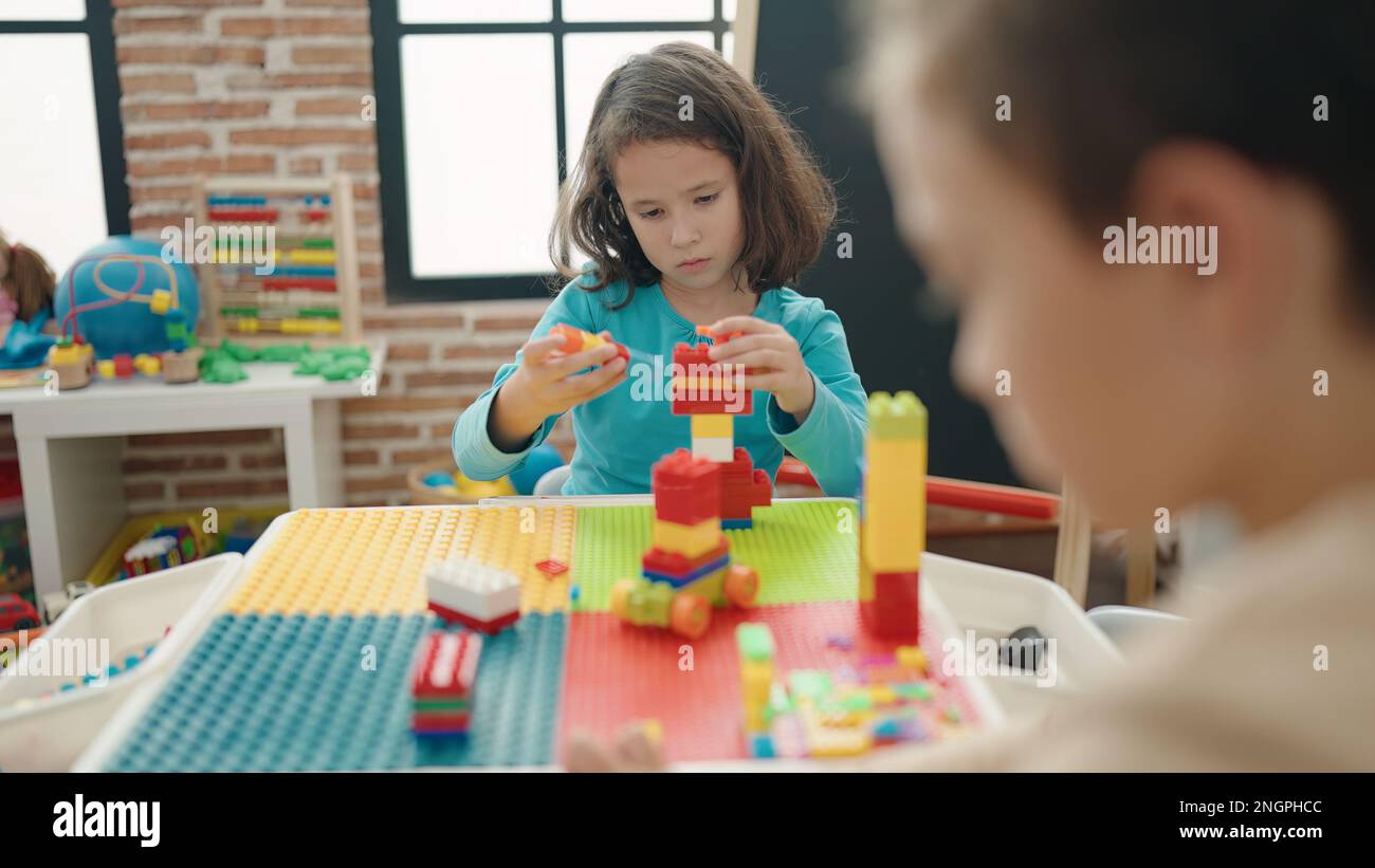 Two kids playing with construction blocks sitting on table at ...
