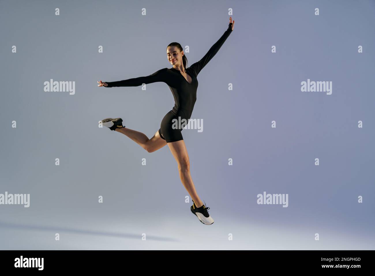 Sporty girl jumping doing split leap in air with joyful expression ...