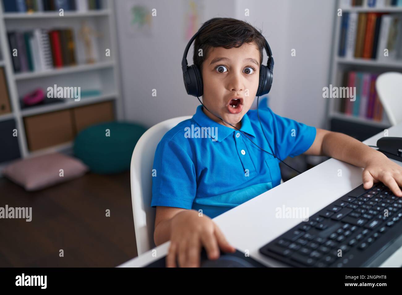 Little hispanic boy using computer laptop at the school scared and ...