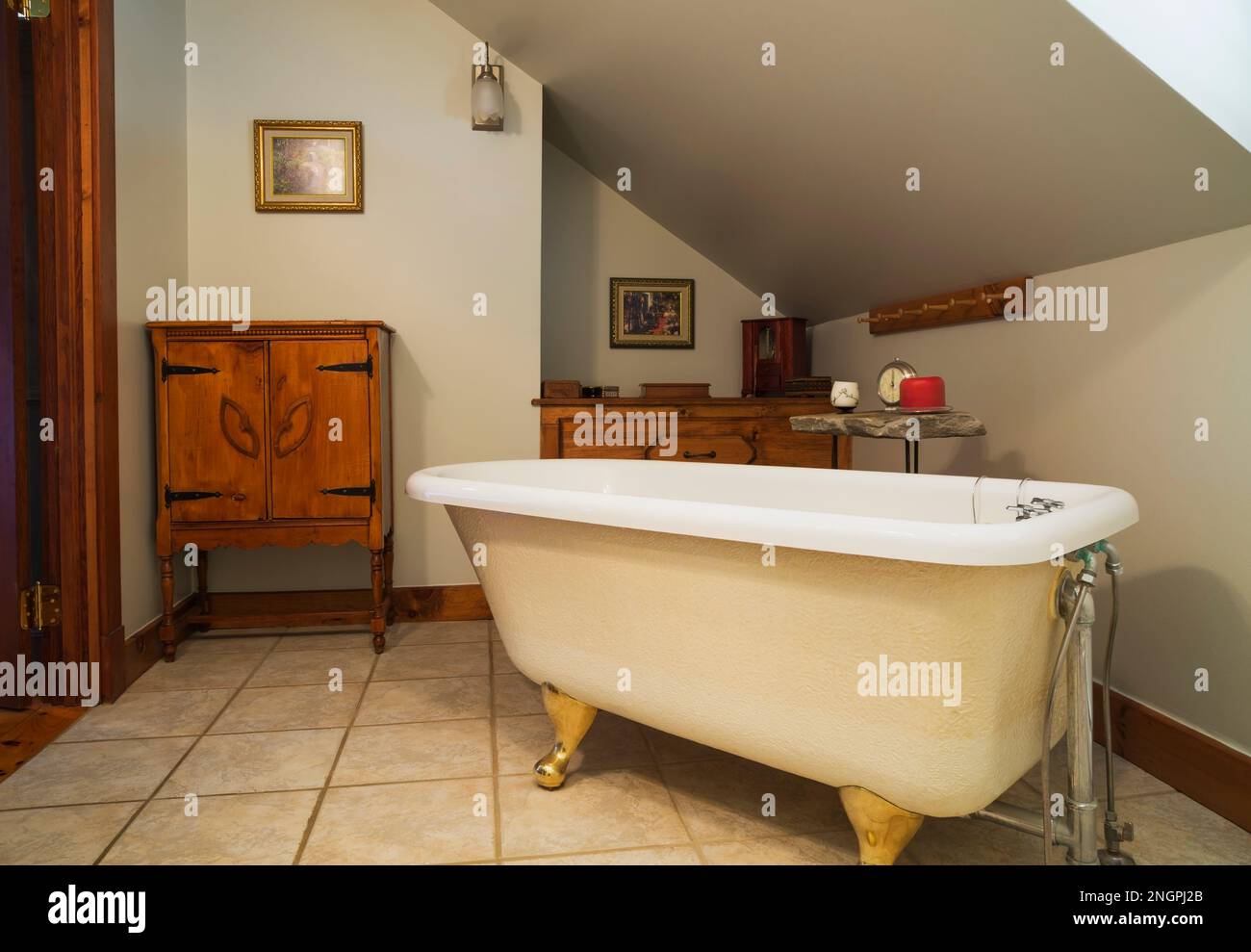White claw foot bathtub and antique pinewood cabinets in en suite with ...