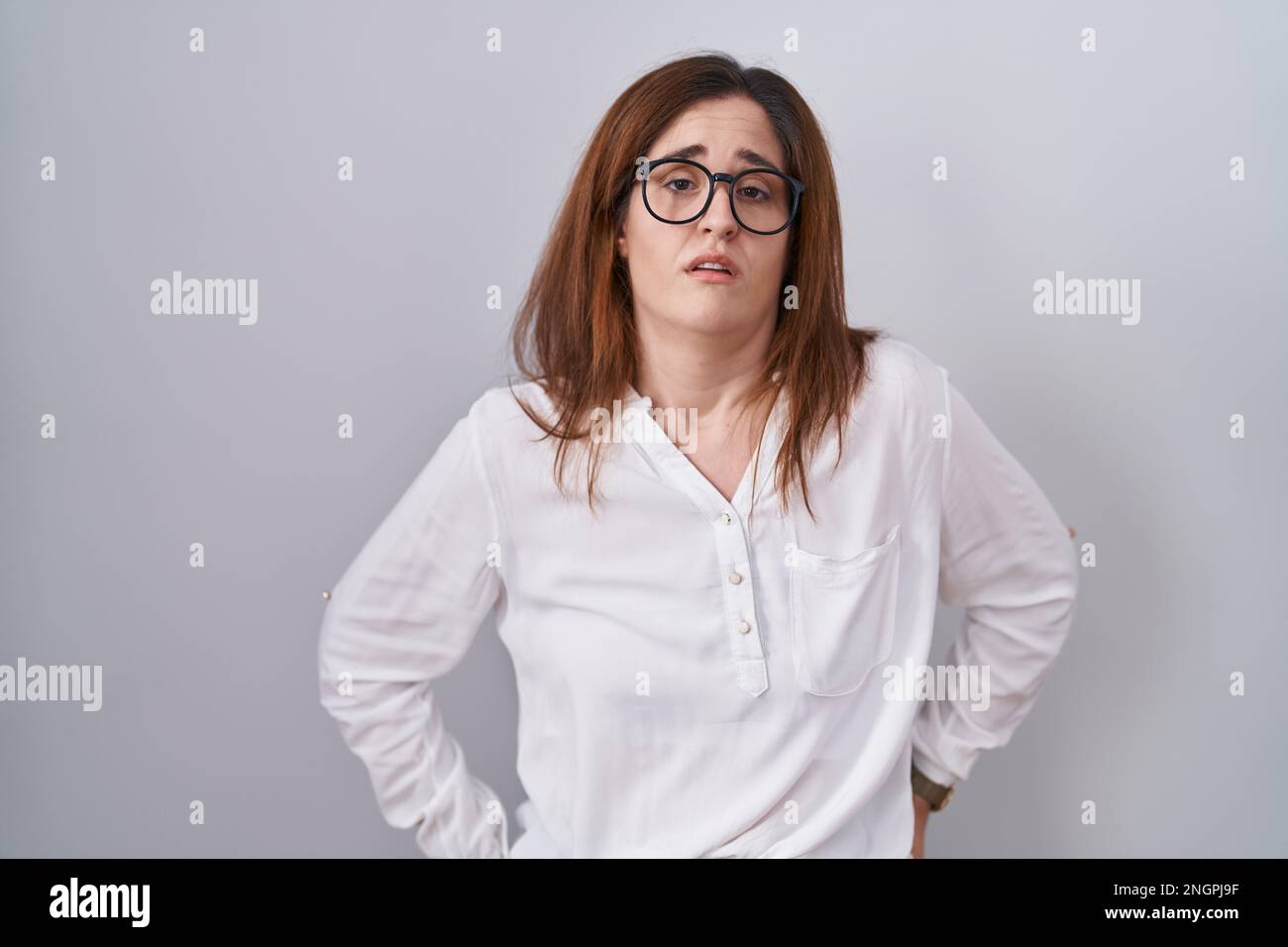 Brunette woman standing over white isolated background looking sleepy ...
