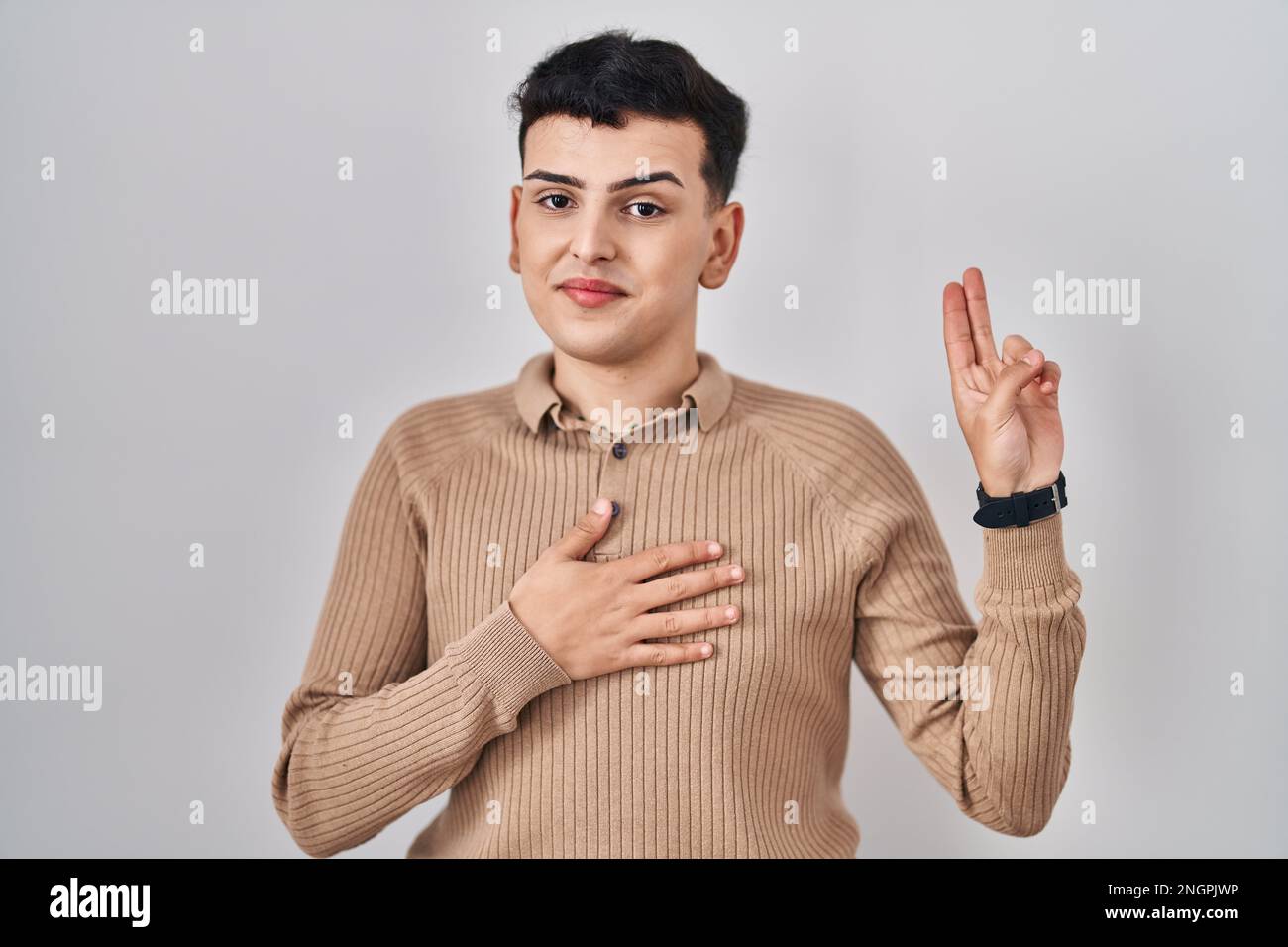 Non binary person standing over isolated background smiling swearing ...
