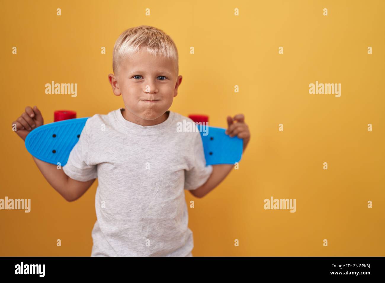 Little caucasian boy holding skate puffing cheeks with funny face ...