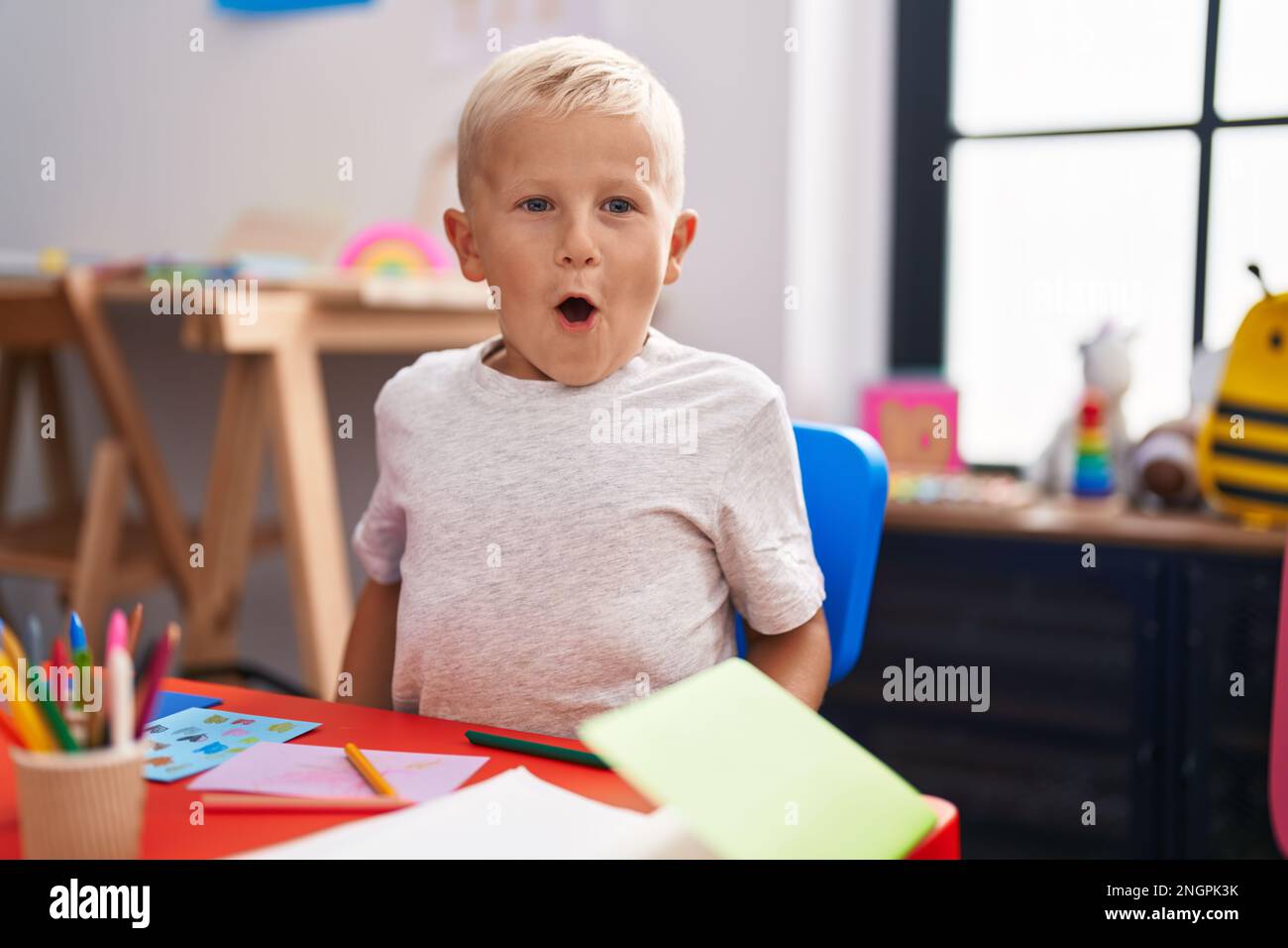 Little caucasian boy painting at the school scared and amazed with open ...