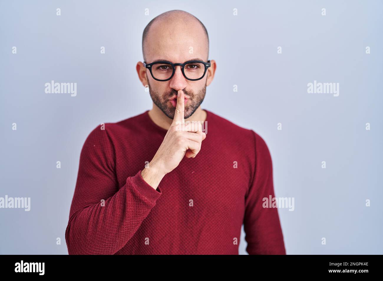 Young bald man with beard standing over white background wearing ...