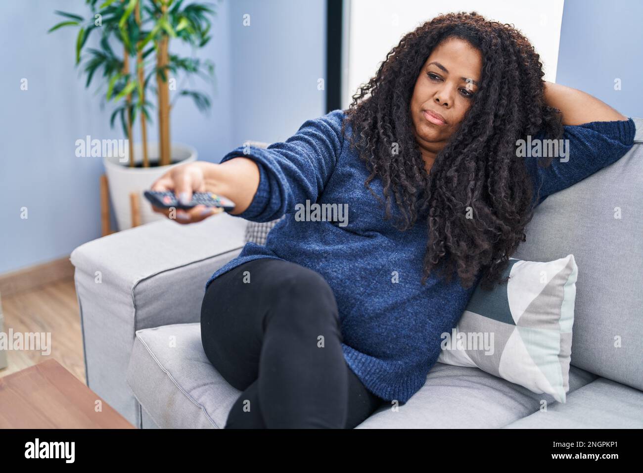 African american woman watching tv lying on sofa with boring expression ...