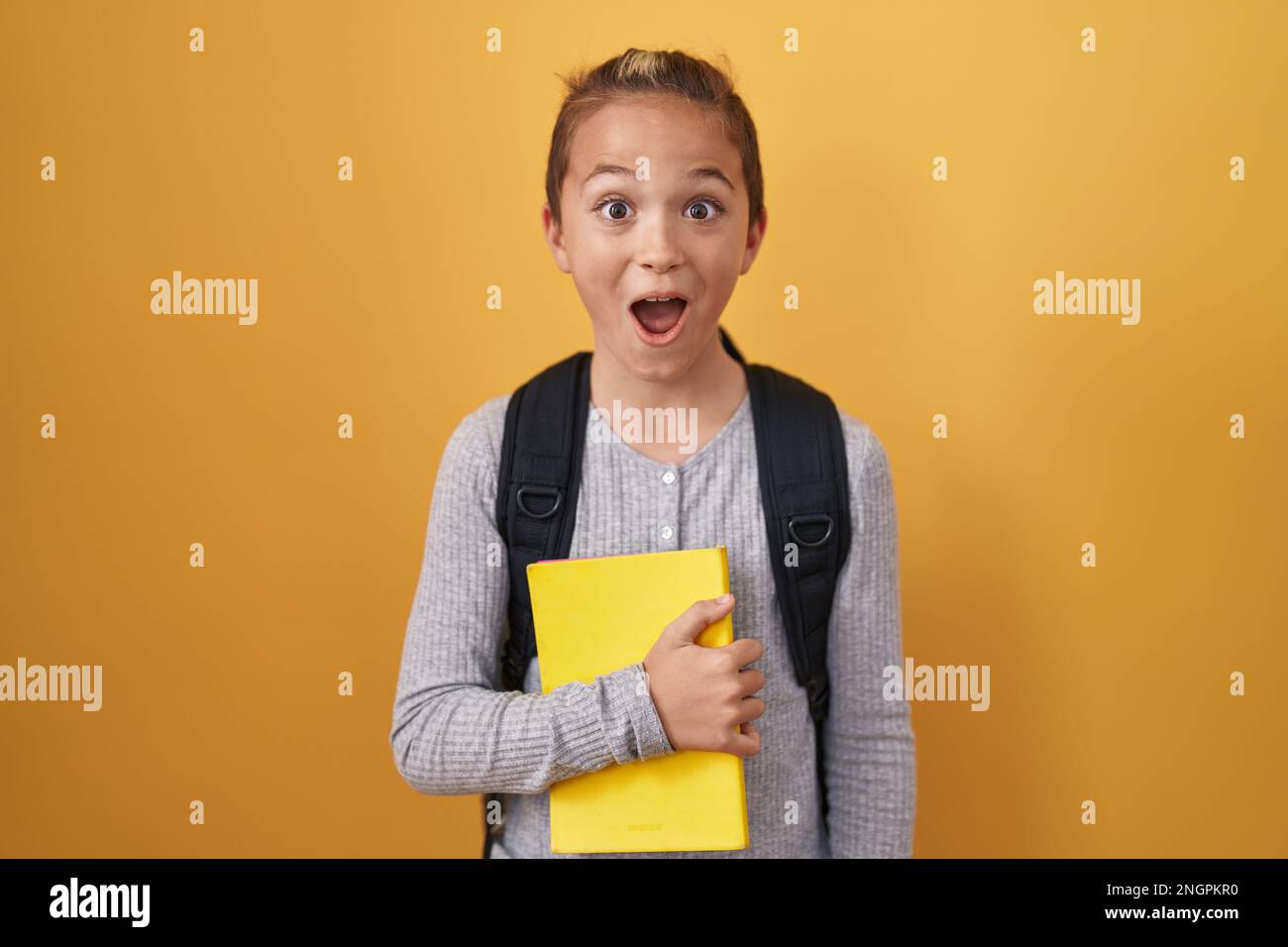 Little caucasian boy wearing student backpack and holding book scared ...