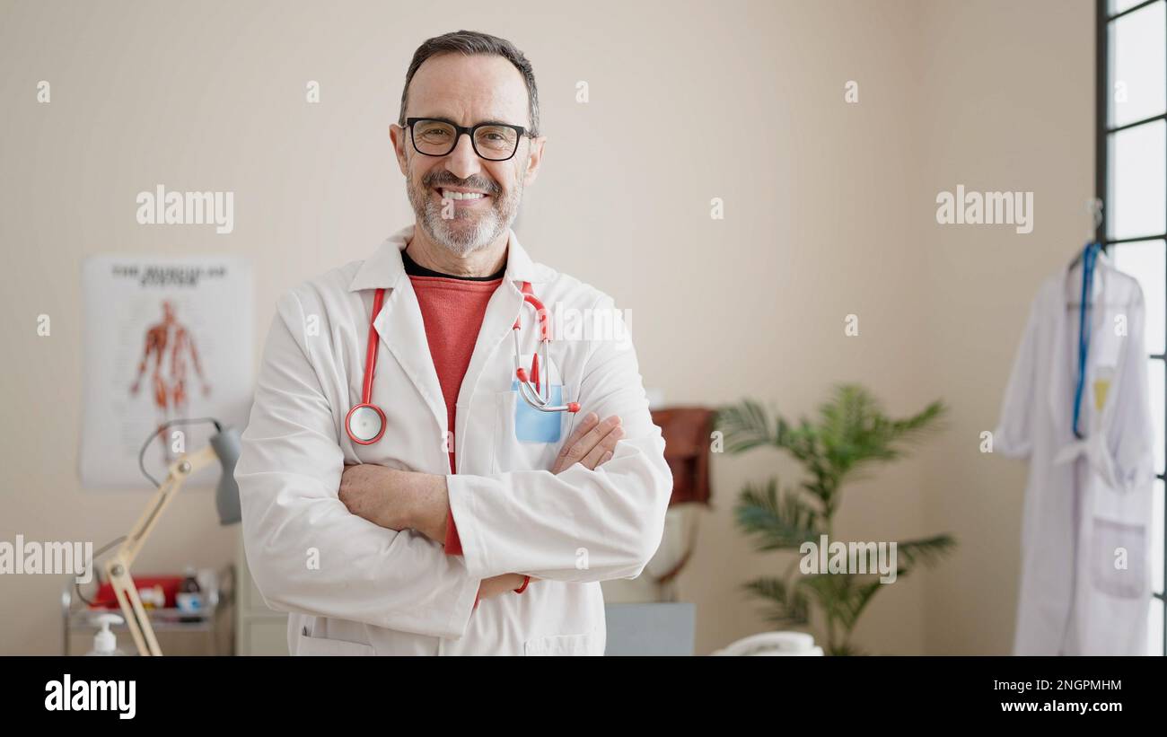 Middle age man doctor smiling confident standing with arms crossed ...