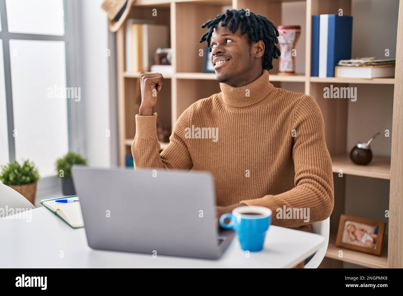 Young african man with dreadlocks working using computer laptop smiling ...