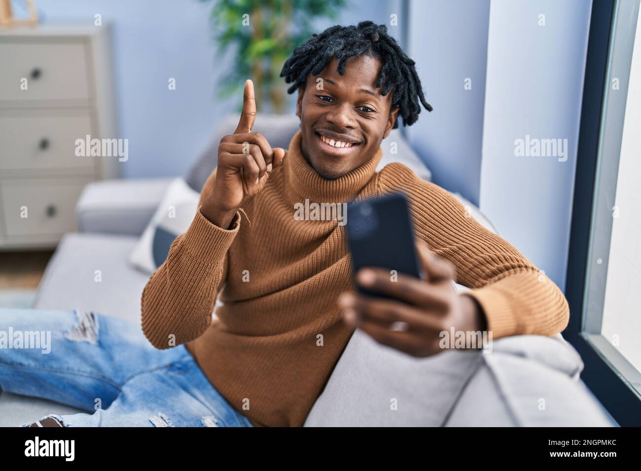 Young african man with dreadlocks using smartphone doing video call ...