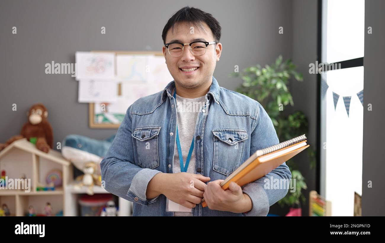 Young chinese man teacher smiling confident holding books at ...