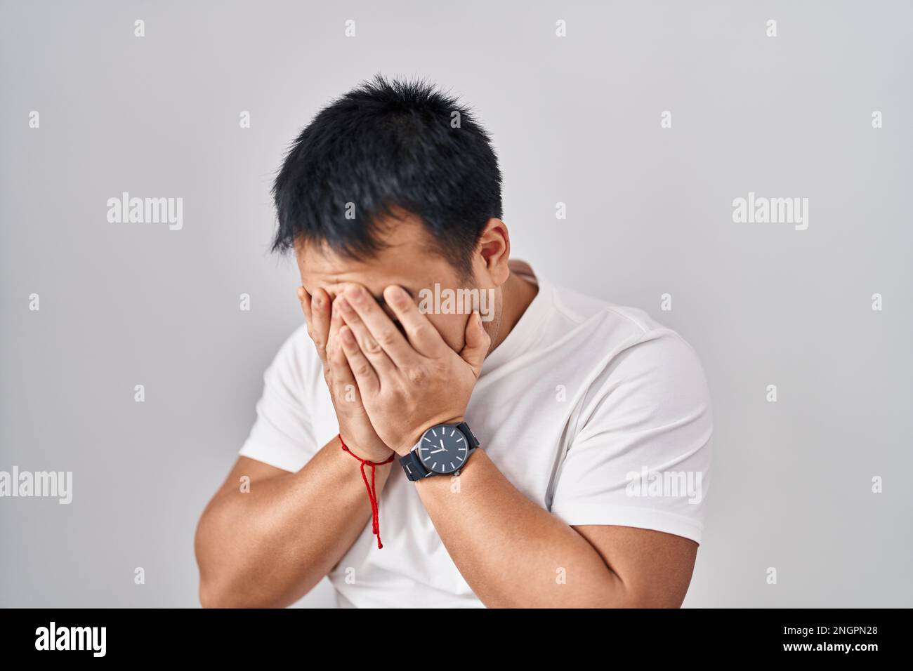 Young chinese man standing over white background with sad expression ...