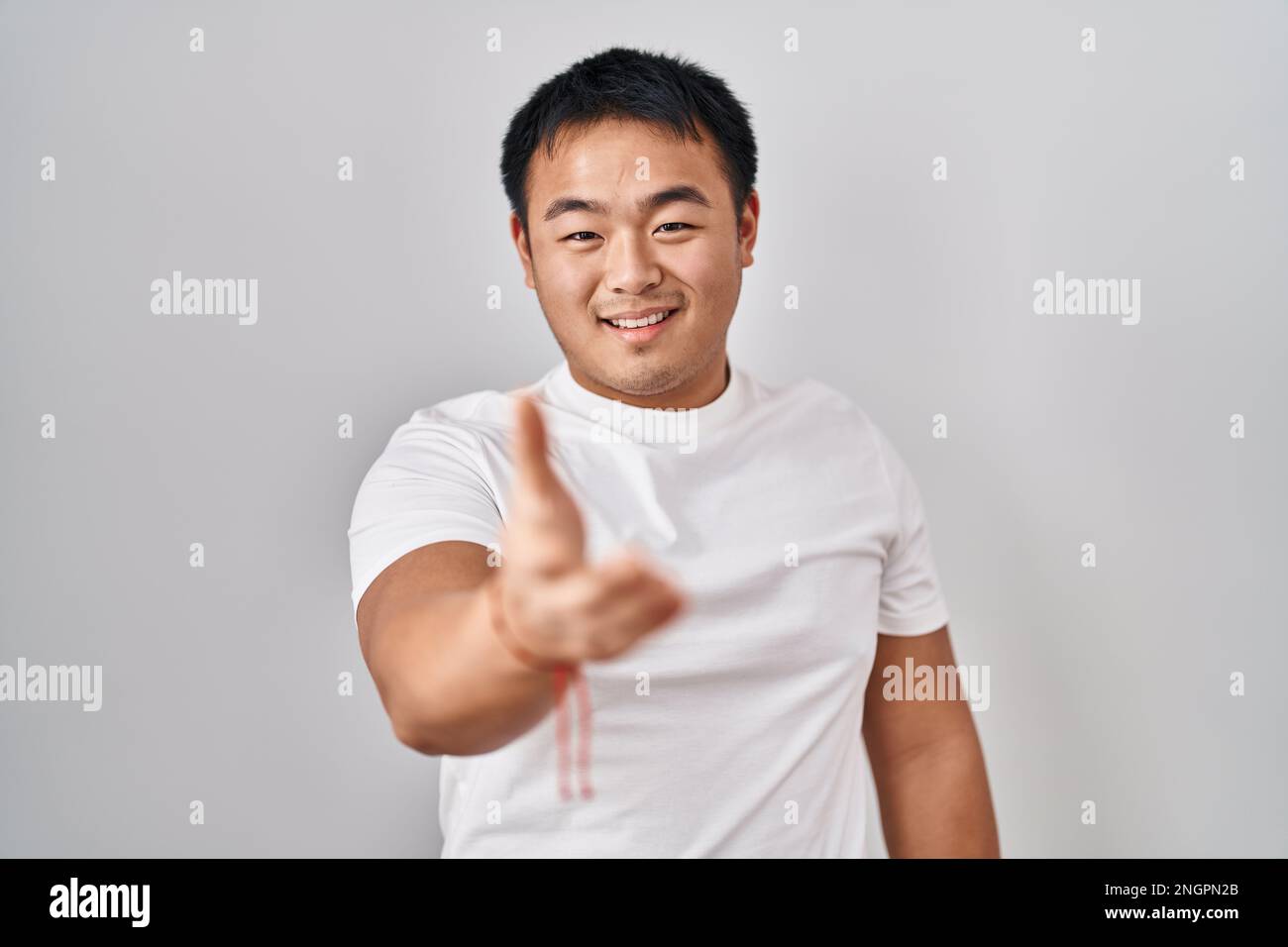Young chinese man standing over white background smiling cheerful ...