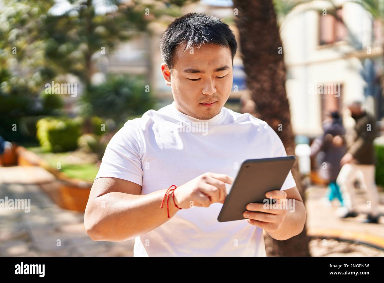 Young chinese man using touchpad at park Stock Photo - Alamy
