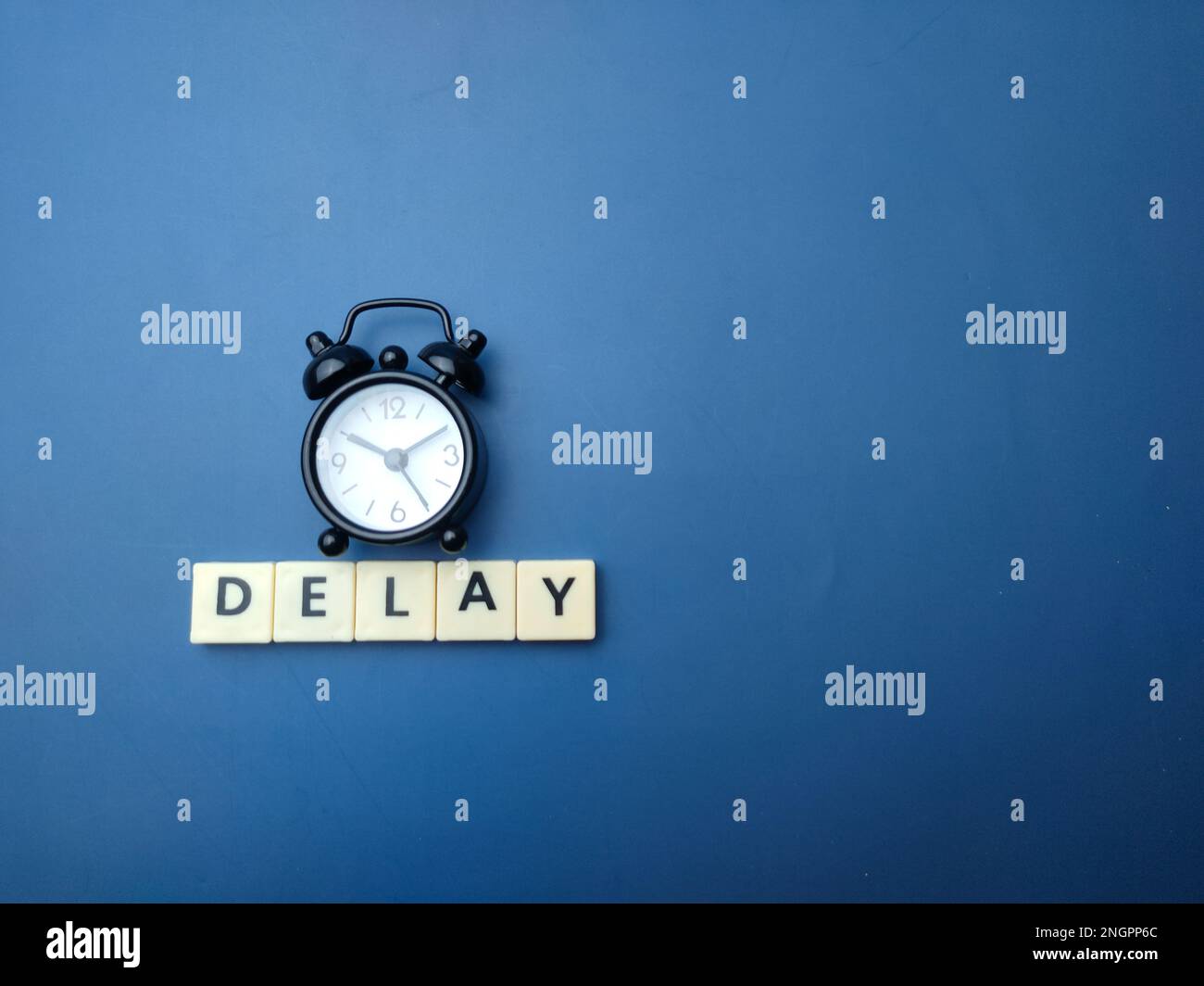 Black alarm clock with the word DELAY on blue background with copy ...