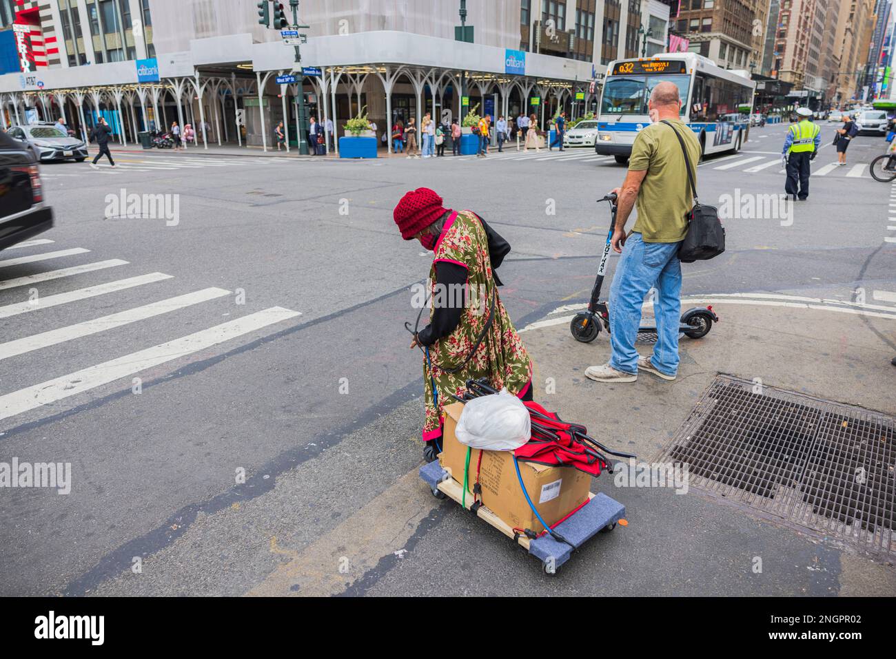 Close-up view of homeless woman with belongings on cart crossing street ...