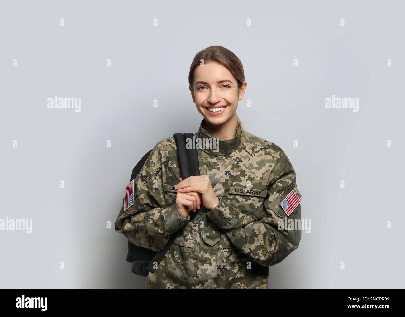 Female cadet with backpack on light grey background. Military education ...