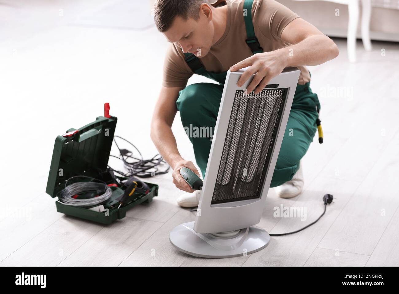 Professional technician repairing electric ultrared heater with screw ...