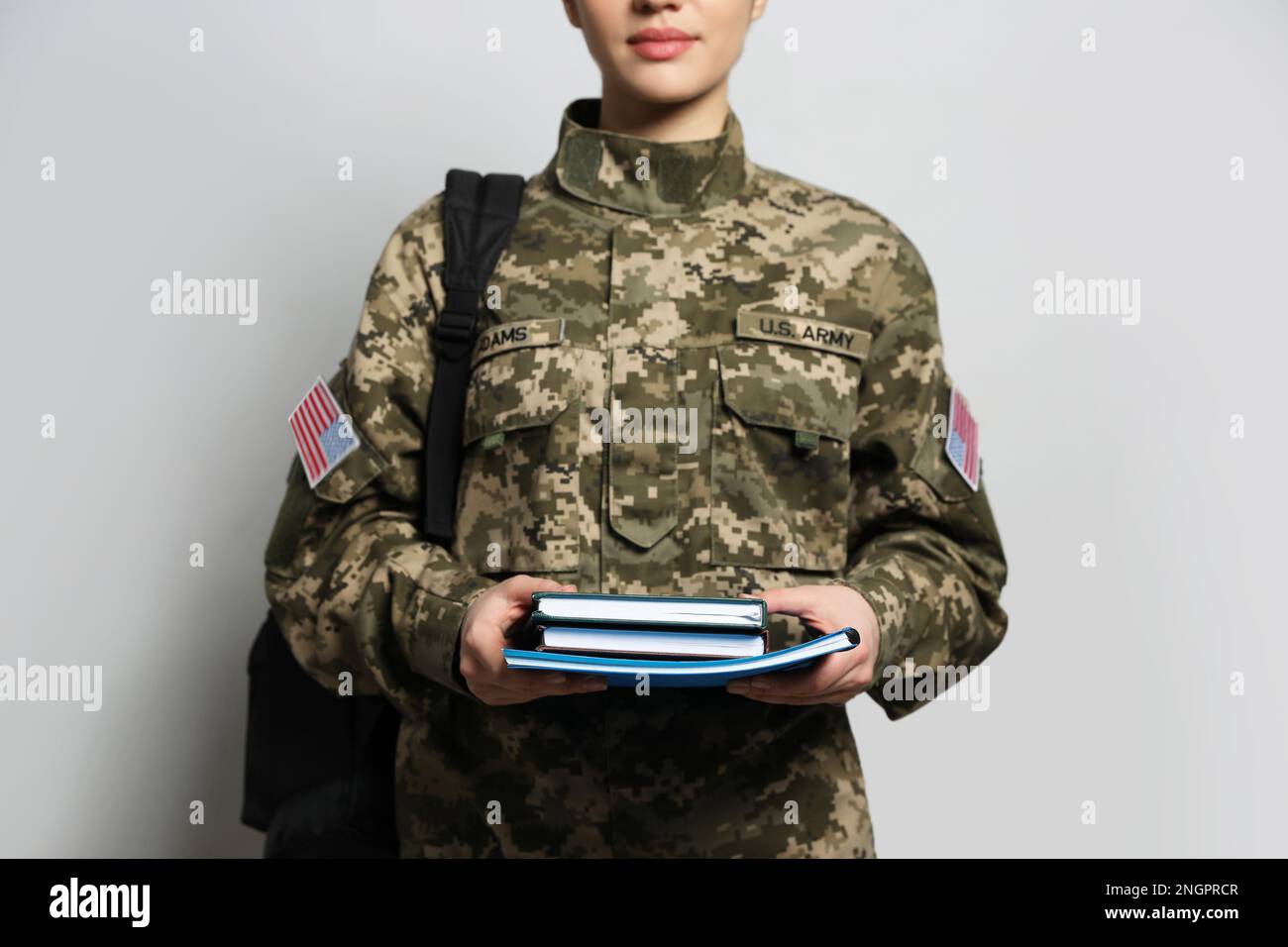 Female soldier with notebooks and backpack on light grey background ...