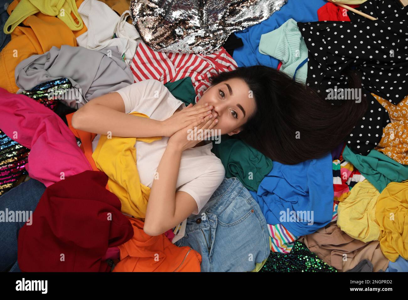 Happy young woman with lots of clothes on floor in room, top view. Fast ...