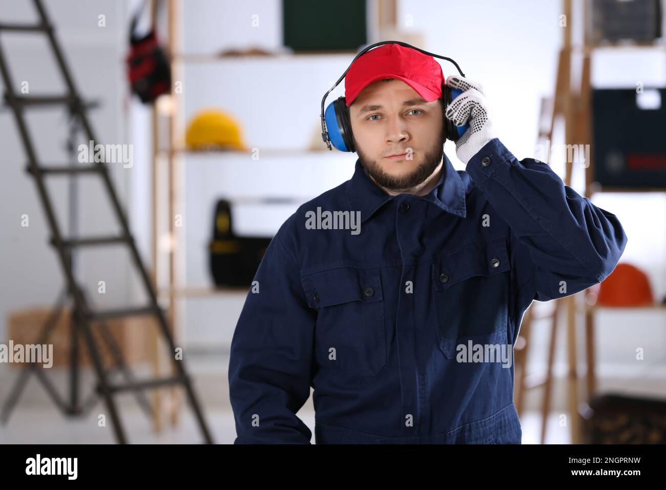 Worker wearing safety headphones indoors. Hearing protection device ...