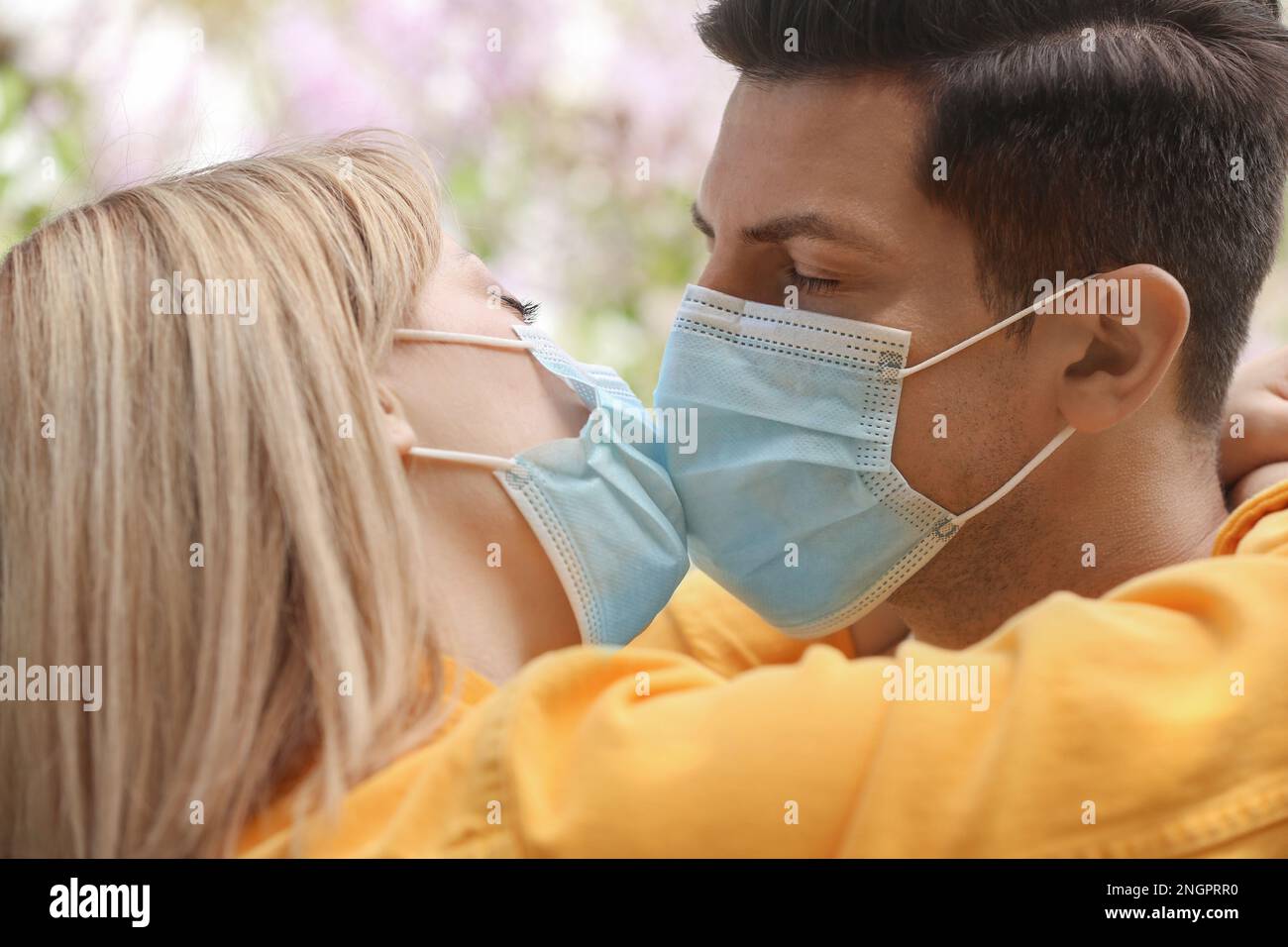 Couple in medical masks trying to kiss outdoors Stock Photo - Alamy