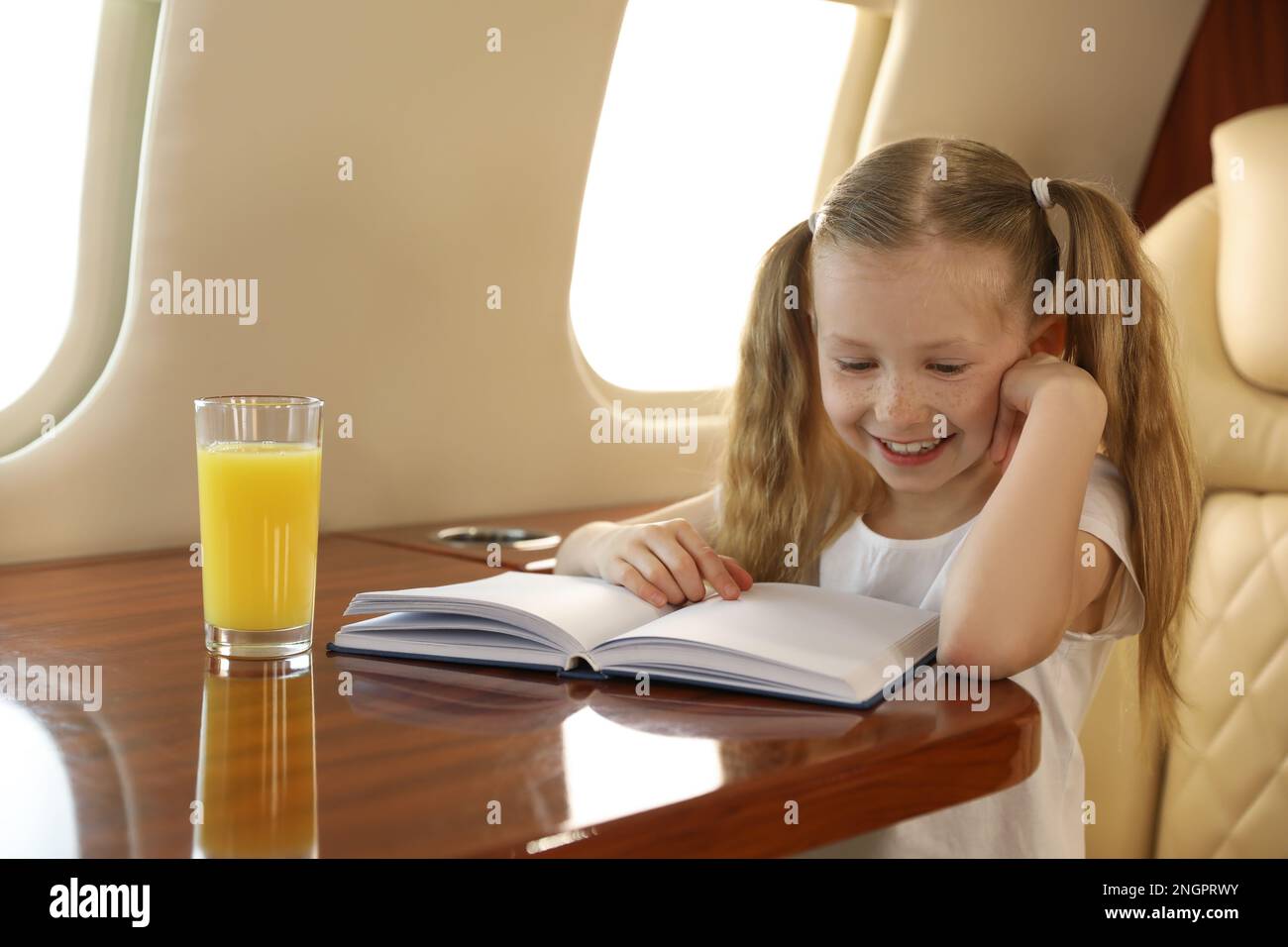 Cute little girl reading book at table in airplane during flight Stock ...
