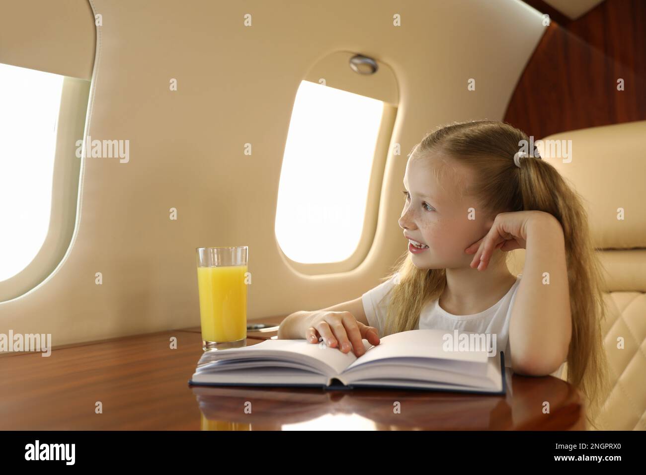 Cute little girl reading book at table in airplane during flight Stock ...