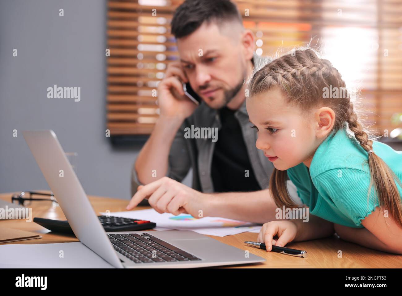 Little girl near laptop in father's office. Combining parenting and ...