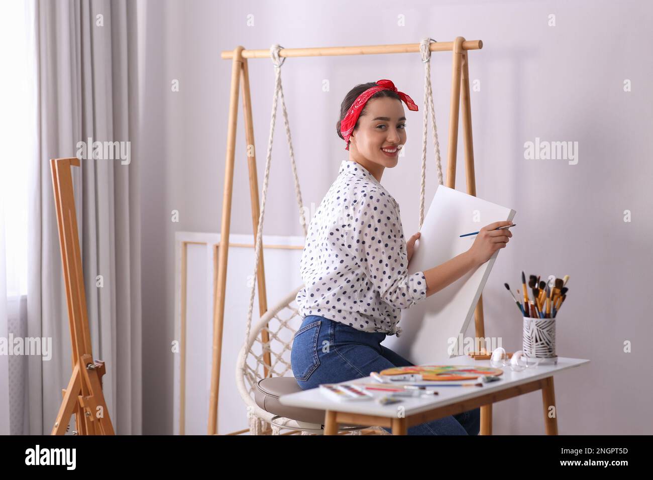 Happy woman artist drawing picture on canvas in studio Stock Photo - Alamy
