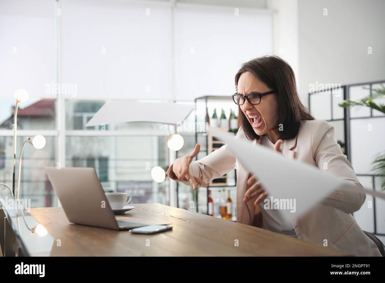 Emotional businesswoman throwing papers at workplace in office. Online ...
