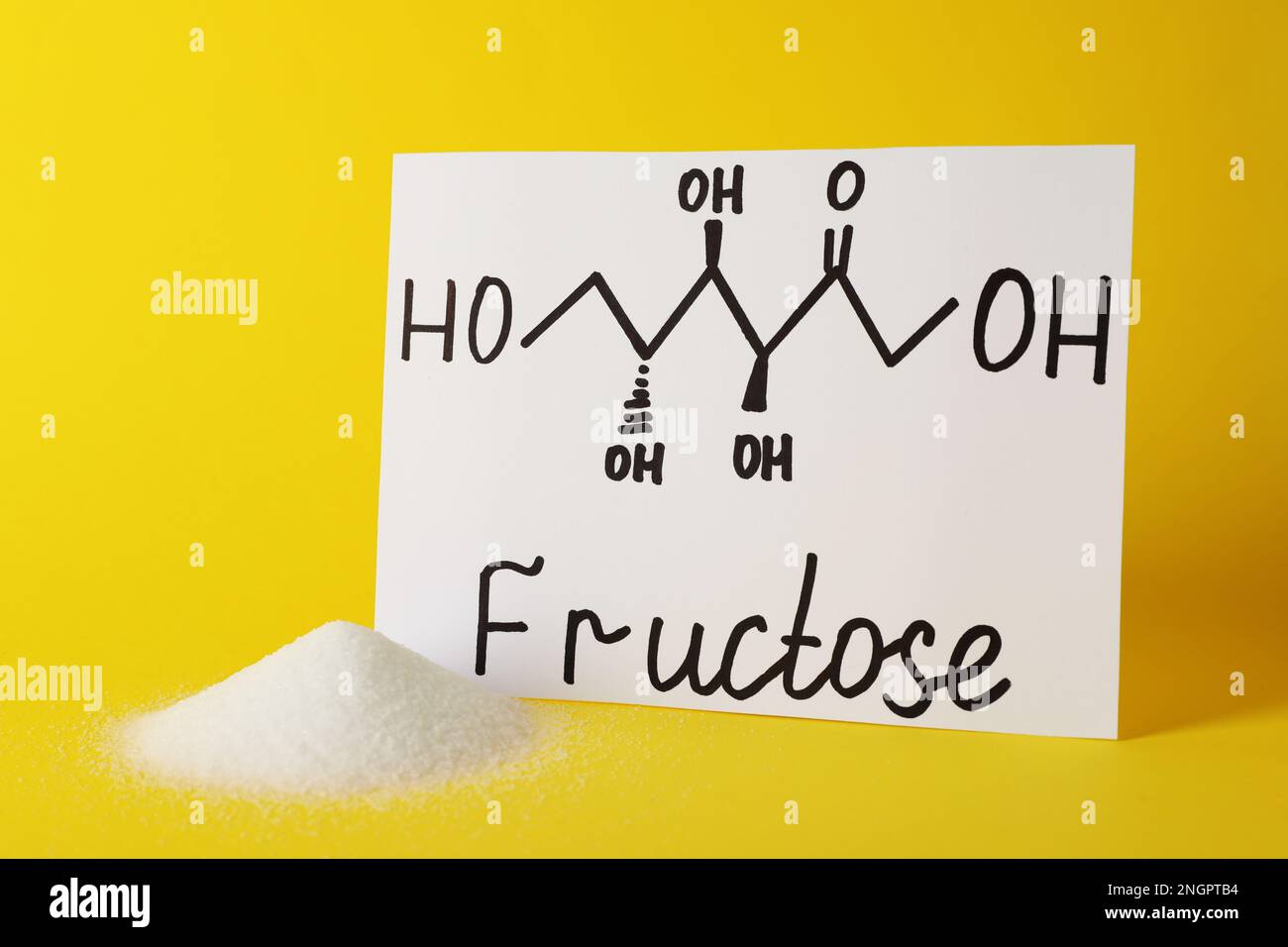 Pile of sugar and word Fructose with drawn scheme on paper against ...