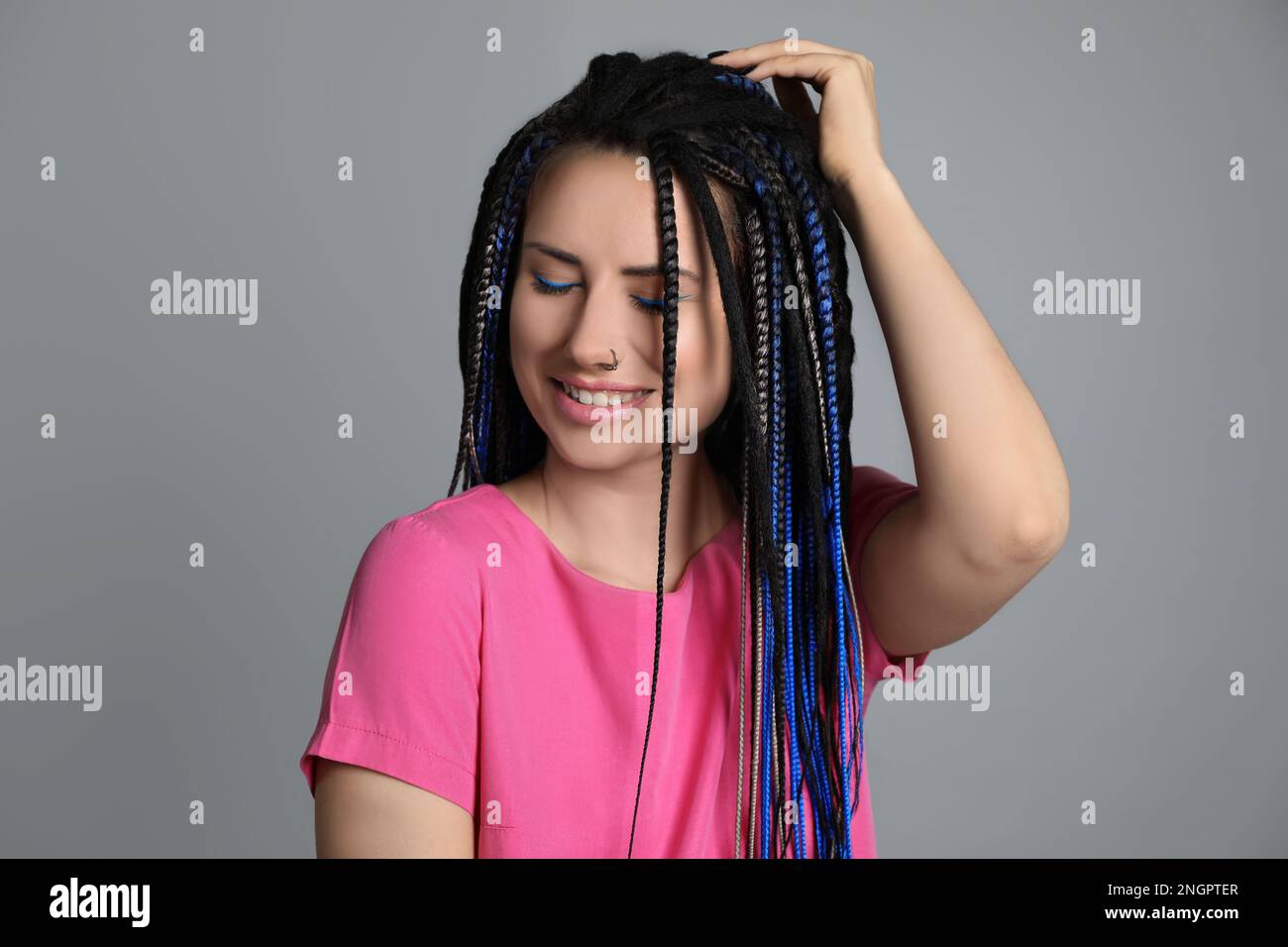 Beautiful young woman with nose piercing and dreadlocks on grey ...